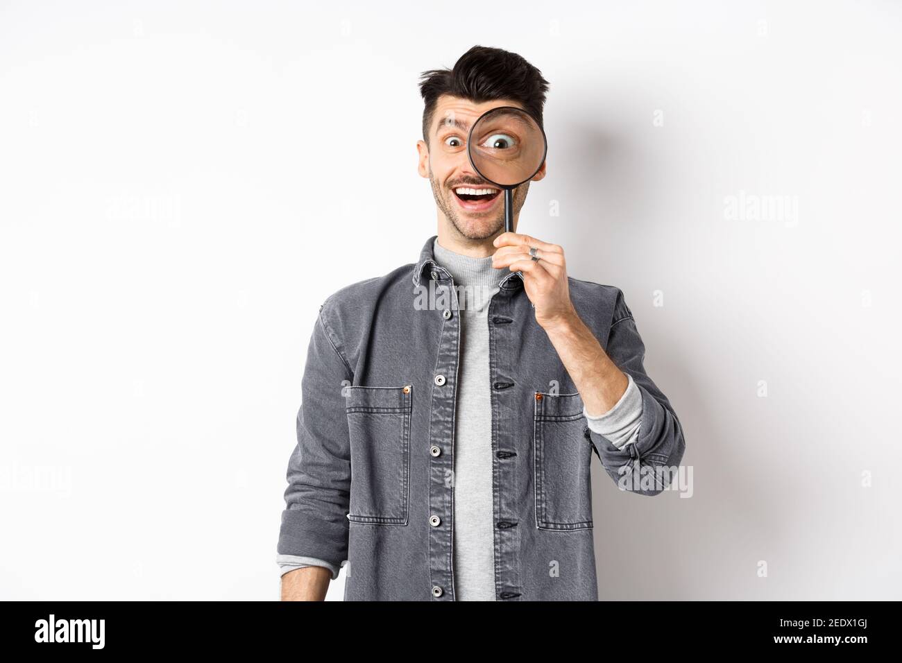 Happy funny guy look through magnifying glass with big eye, checking ...