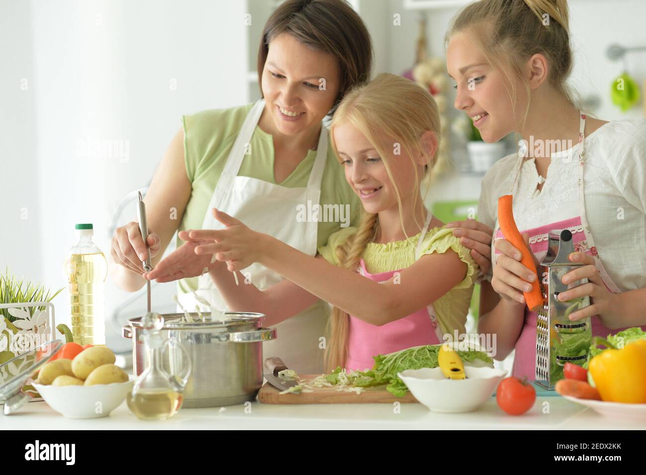 Cute girls with mother cooking in kitchen Stock Photo - Alamy