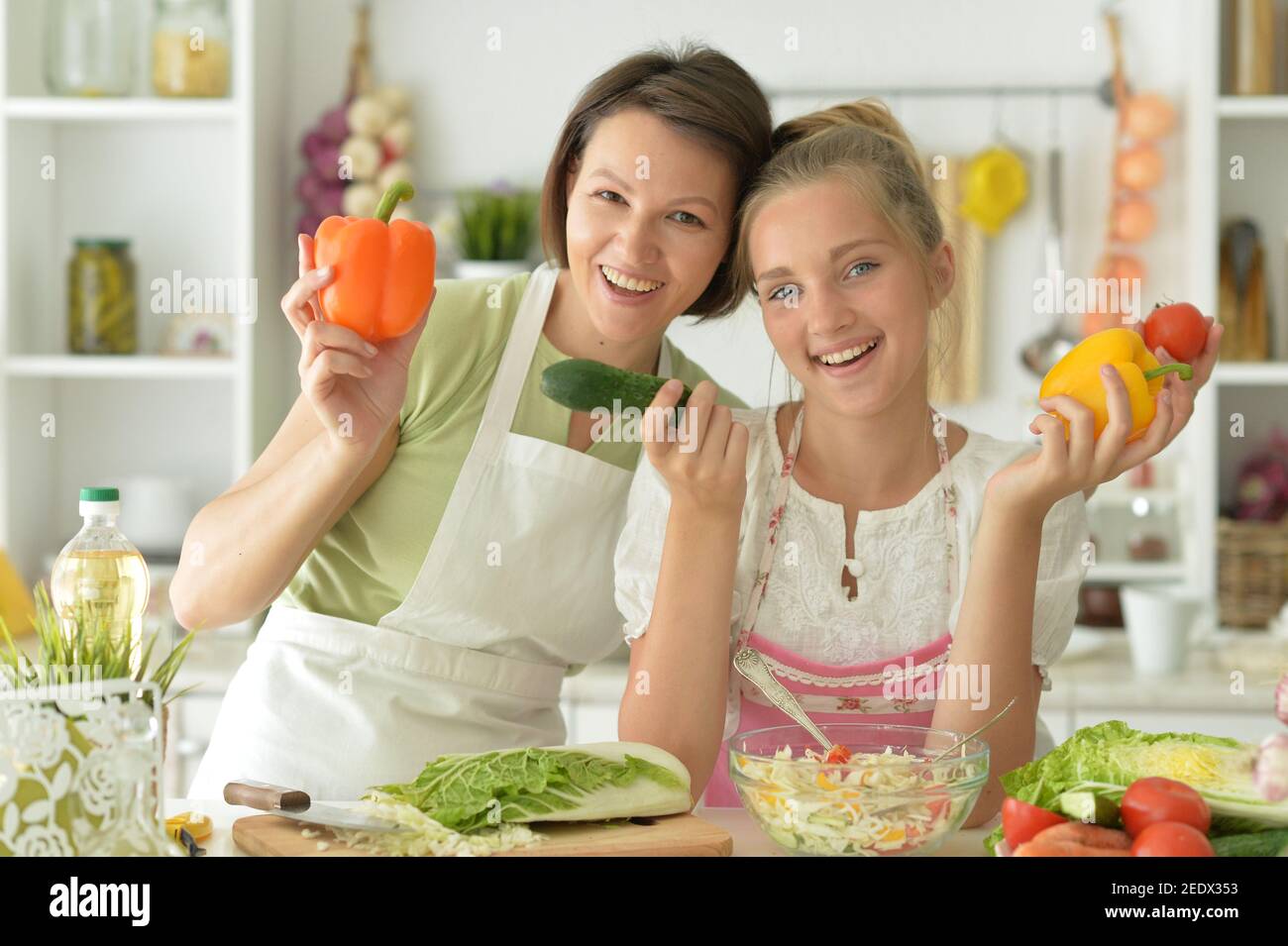 Teenager girl with her mother cooking together at kitchen table Stock ...