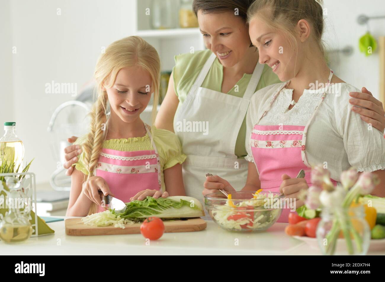 Cute girls with mother cooking in kitchen Stock Photo - Alamy