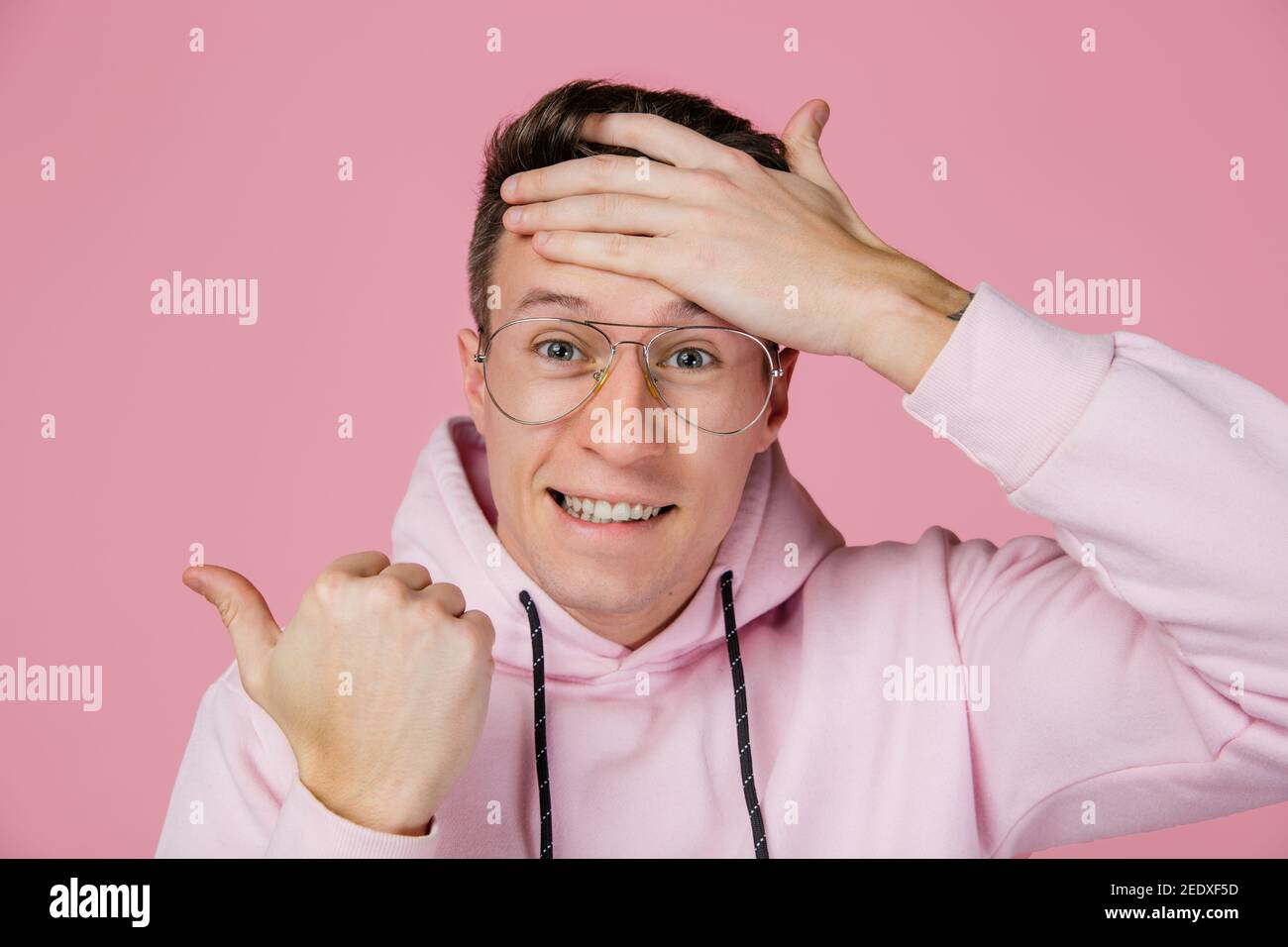 Shocked pointing at side. Caucasian man's portrait isolated on pink ...