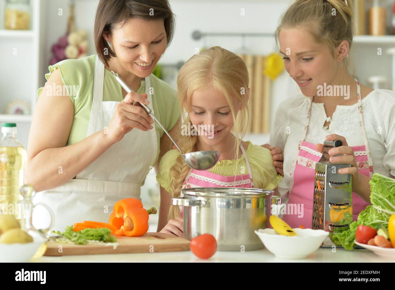 Cute girls with mother cooking in kitchen Stock Photo - Alamy