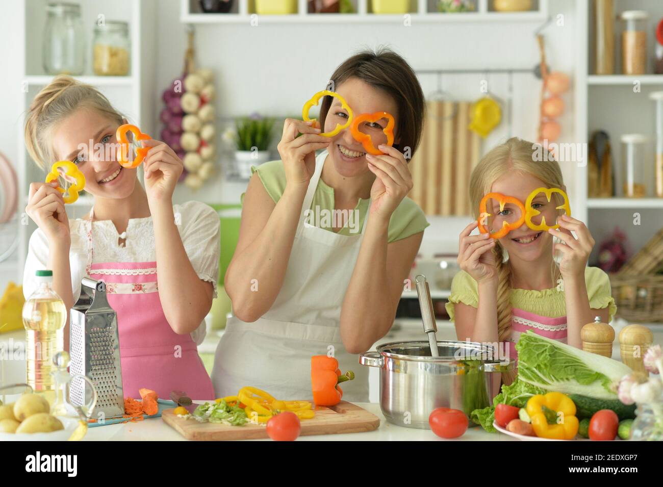 Cute girls with mother cooking in kitchen Stock Photo - Alamy