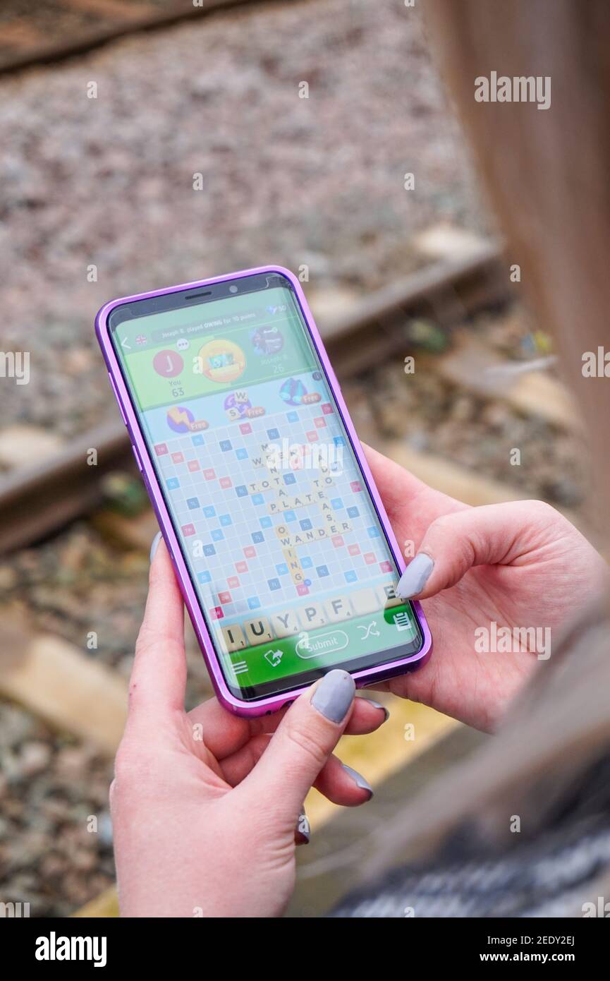 woman on phone, mobile playing games app waiting for train commute ...