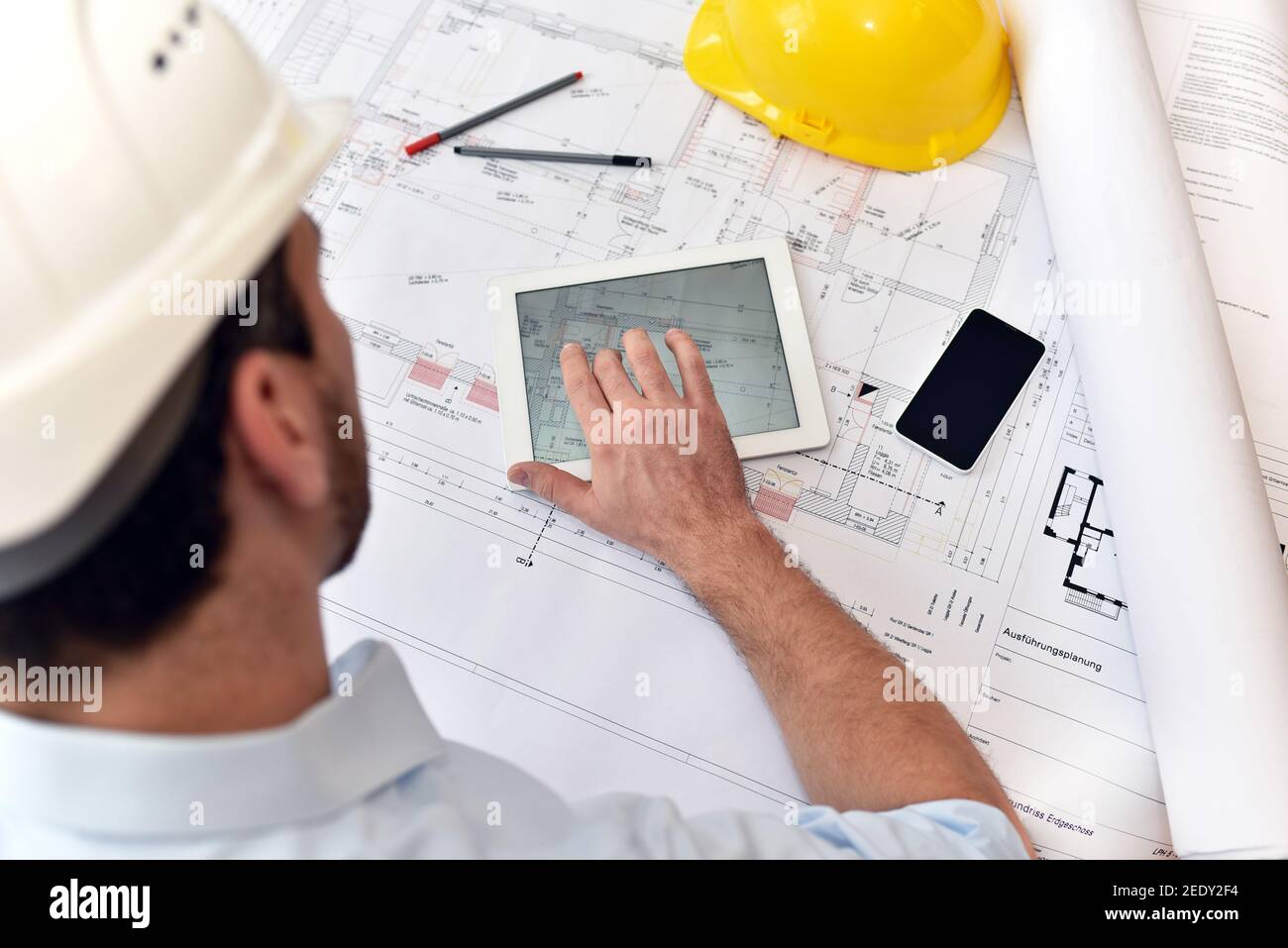 Architect / engineer at his desk planning the construction of a house ...