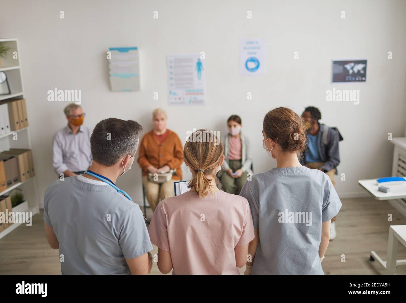 Back view portrait of group of doctors looking at patients waiting in ...