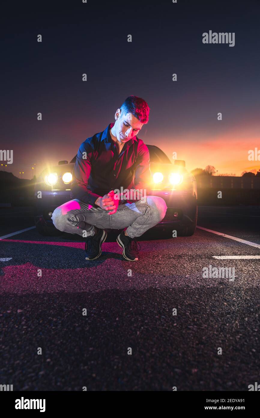 Young man with a sports car at a parking lot with color lights Stock ...