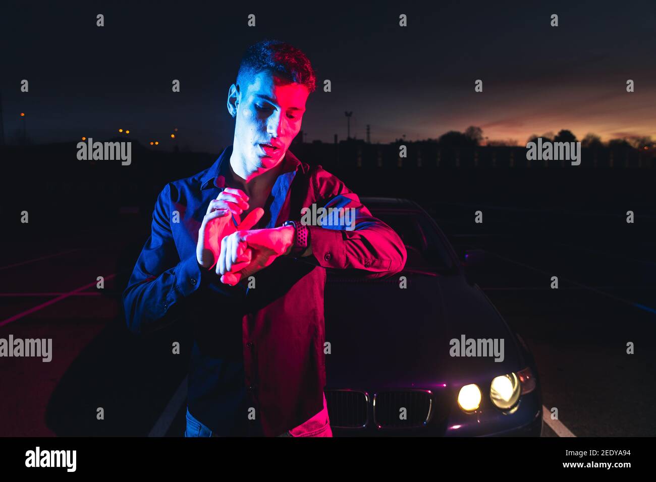 Young man with a sports car at a parking lot with color lights Stock ...