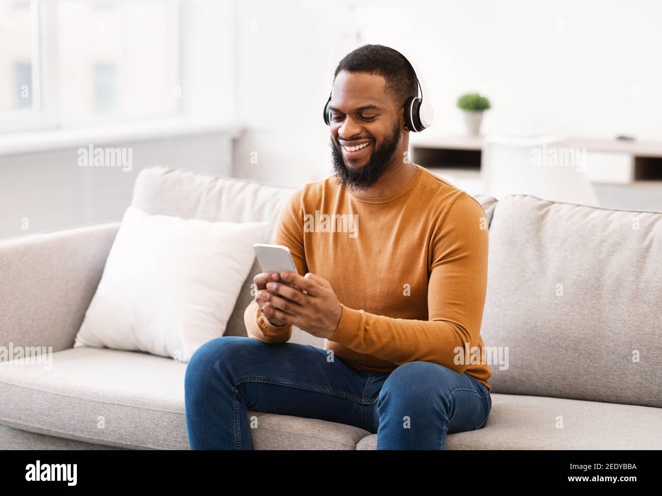 Black Guy Wearing Headphones Using Smartphone Listening To Music Indoor ...