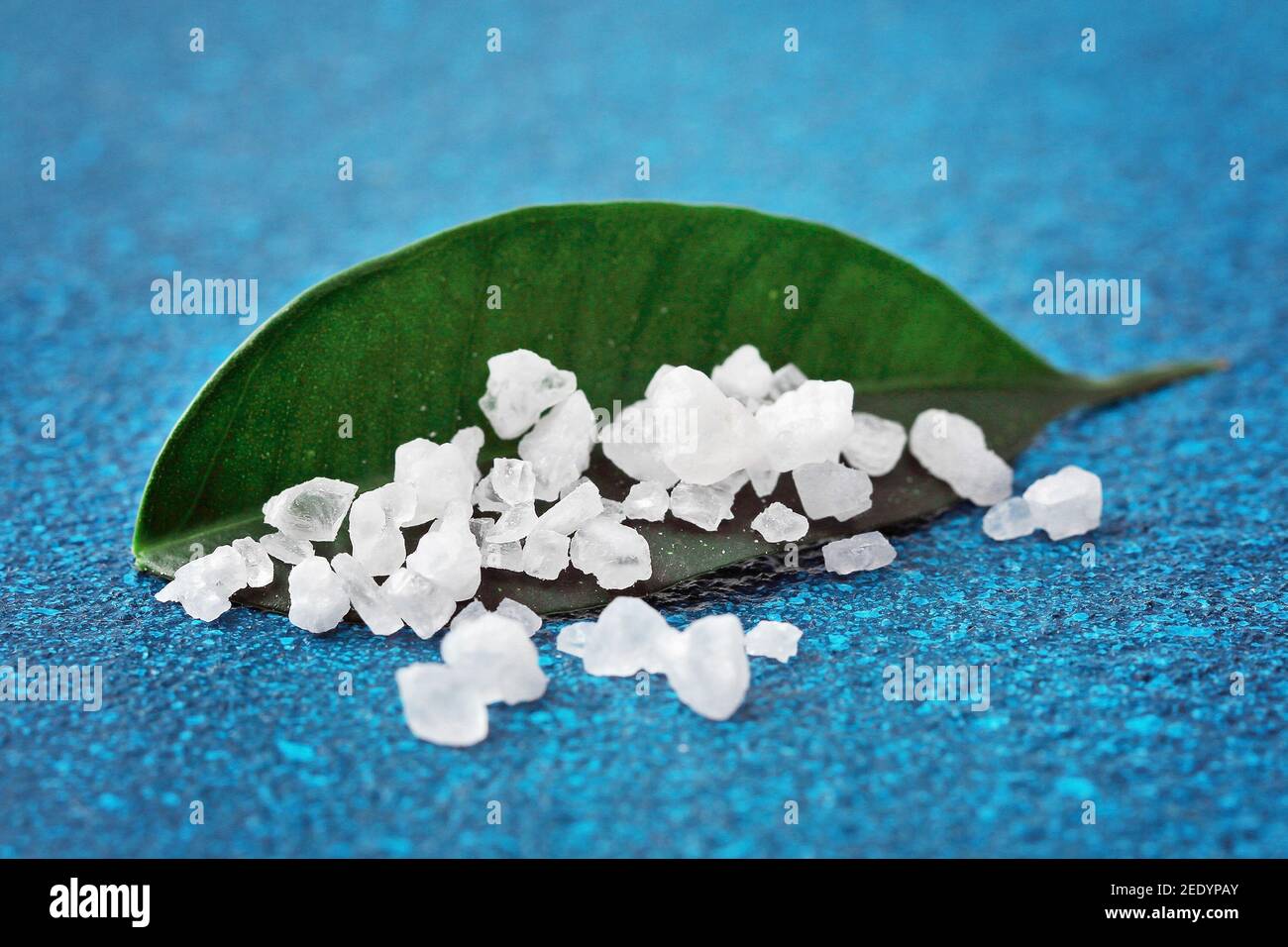 Coarse salt crystals on a blue table. sea salt. Background for ...