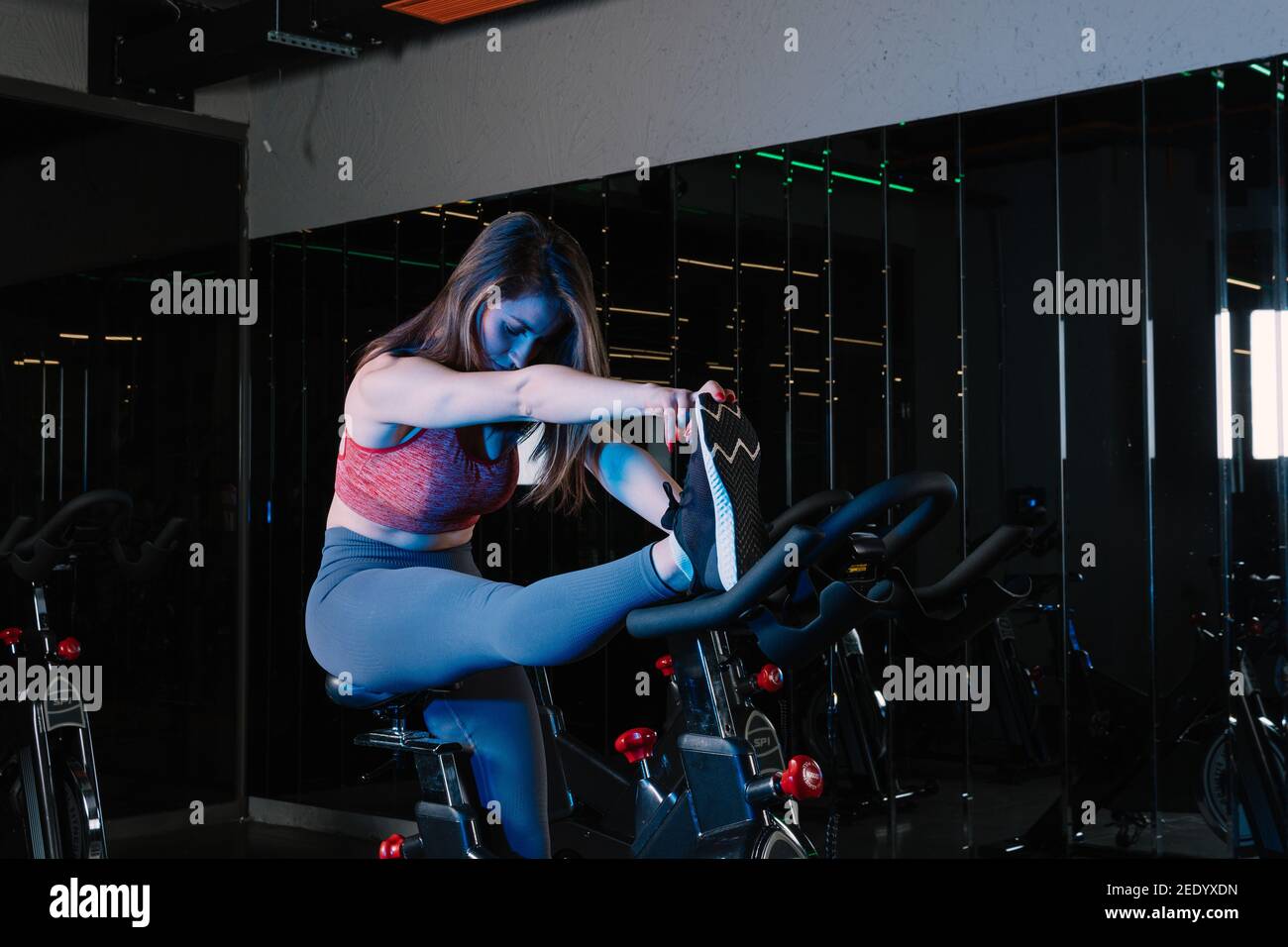 Beautiful woman with red sports bra and black tights poses on bicycle ...
