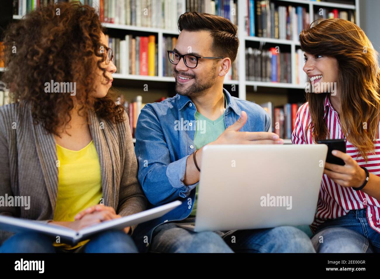 Group of happy students reading books and preparing to exam in library ...