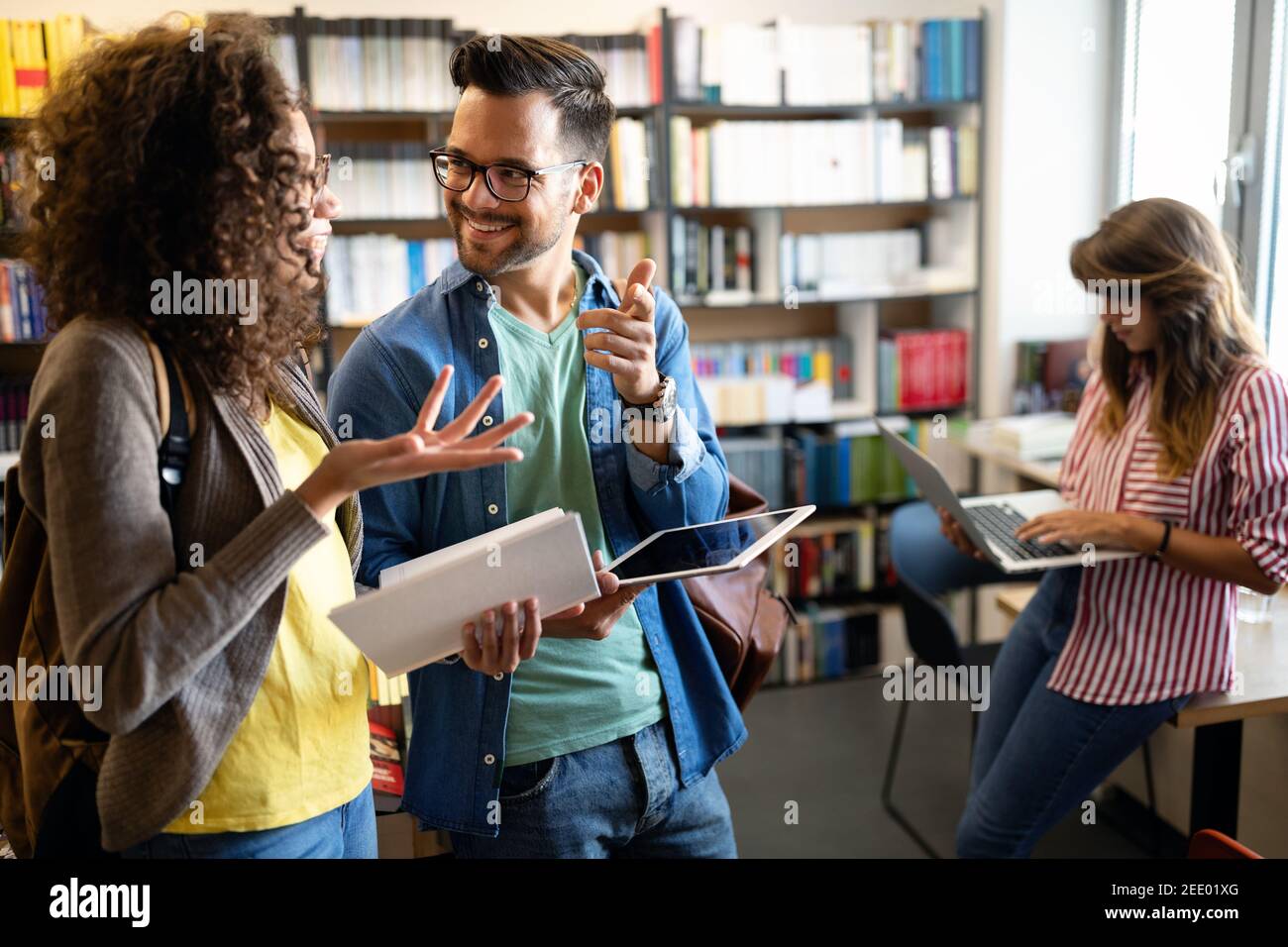 Group of happy students reading books and preparing to exam in library ...