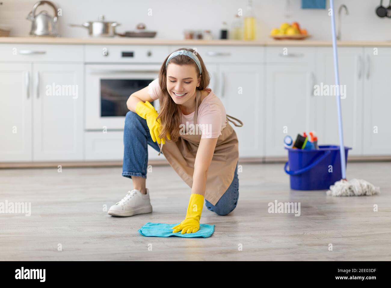 Professional cleaning service. Cheerful young lady in apron and rubber ...