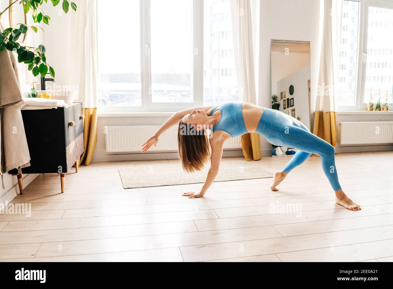 Portrait of beautiful young woman practicing yoga indoor. Woman in blue sportswear practice wild ...