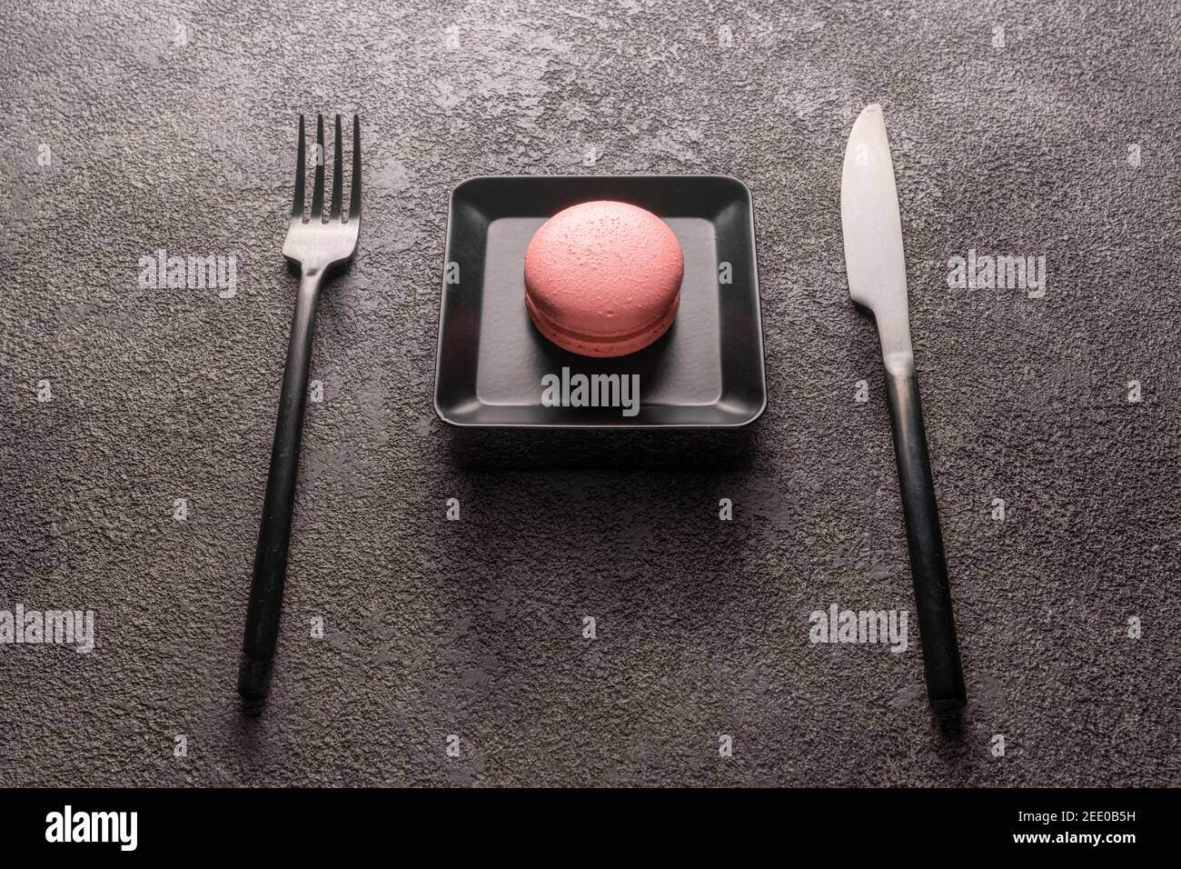 pink macaroon cake in a black small plate. a beautiful food photo, a ...