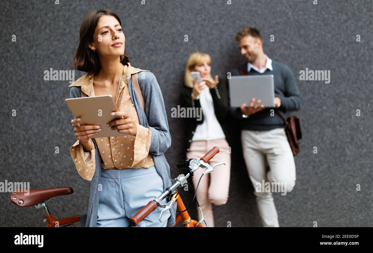 Group of young business people holding different digital devices ...