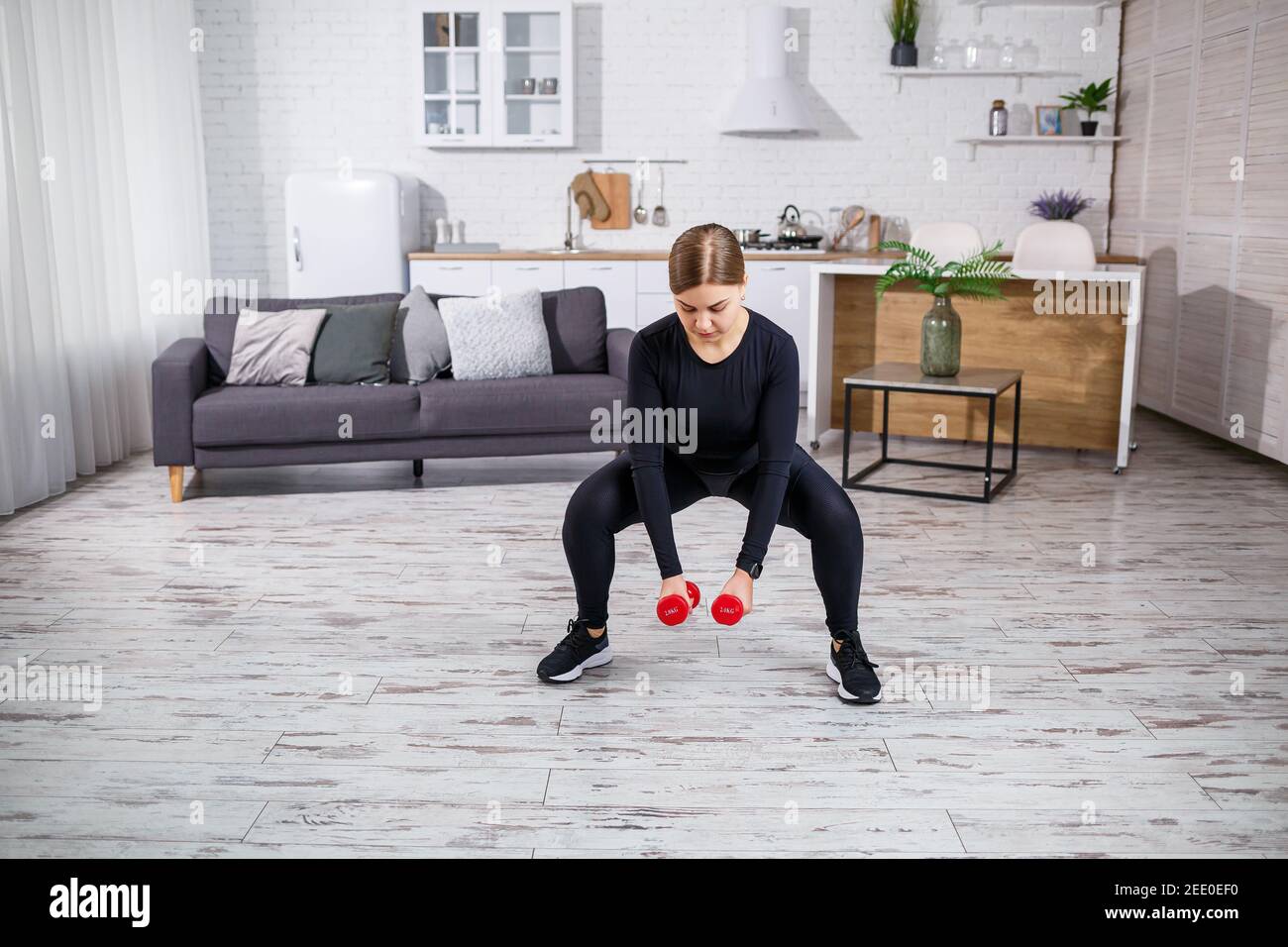 A slender woman goes in for sports at home in a top and leggings ...