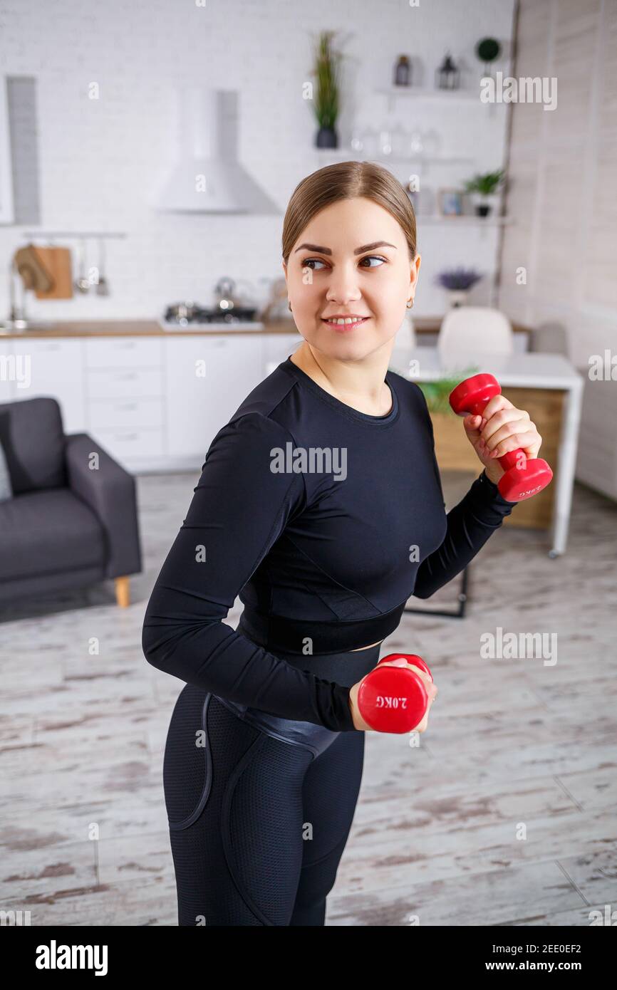 Portrait of a slender woman goes in for sports at home, on her top and ...