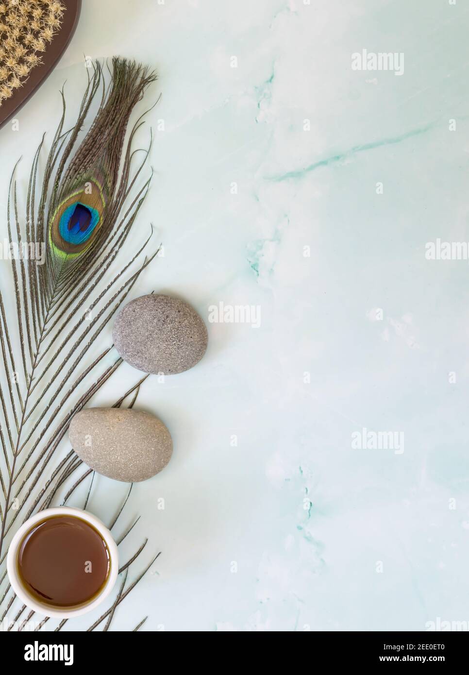 Flat lay composition with peacock feather, massage stones, oil and body ...