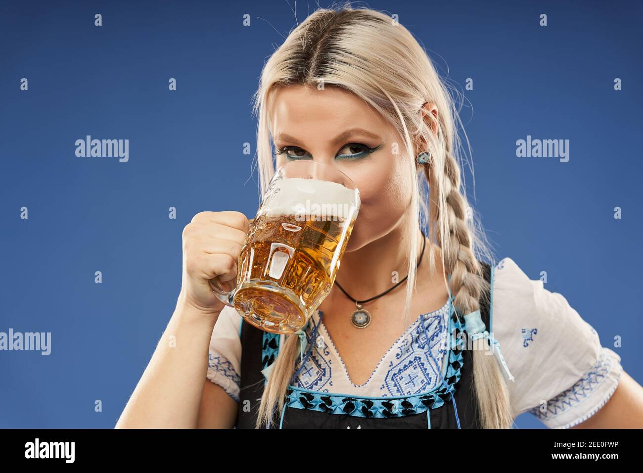 Blonde German young woman in traditional costume with a pint of beer ...