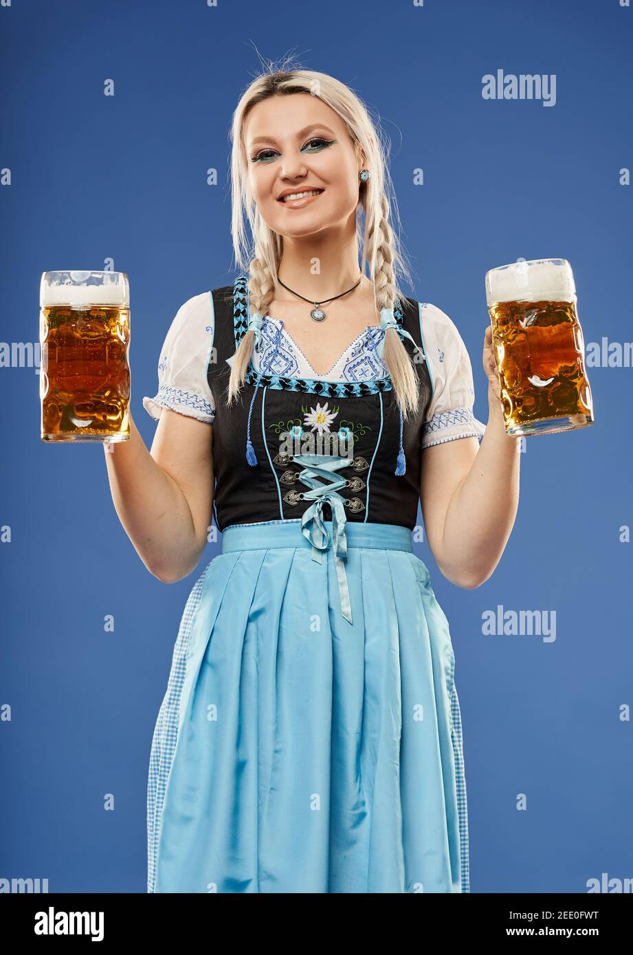 Blonde German young woman in traditional costume with a pint of beer ...