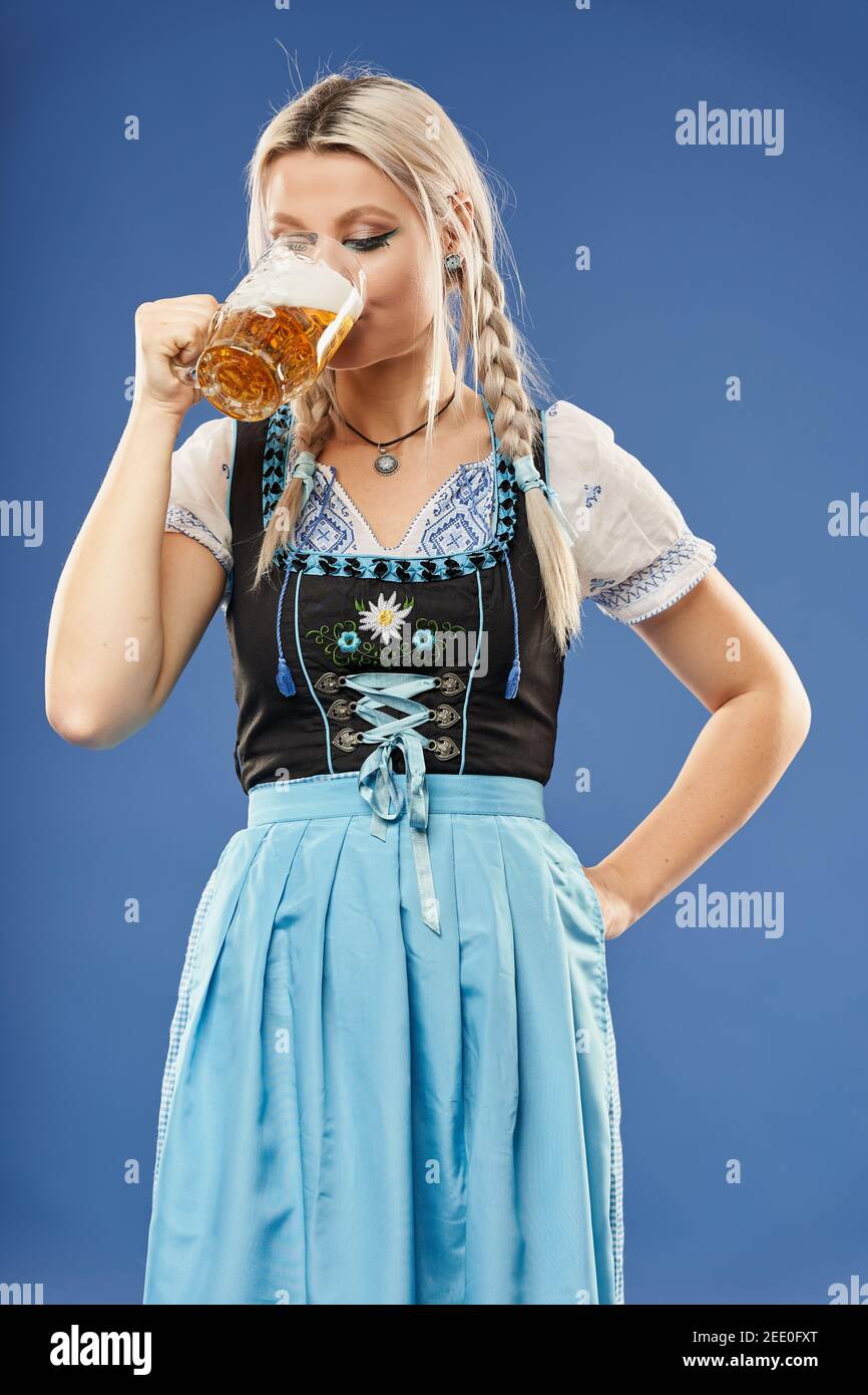 Blonde German young woman in traditional costume with a pint of beer ...