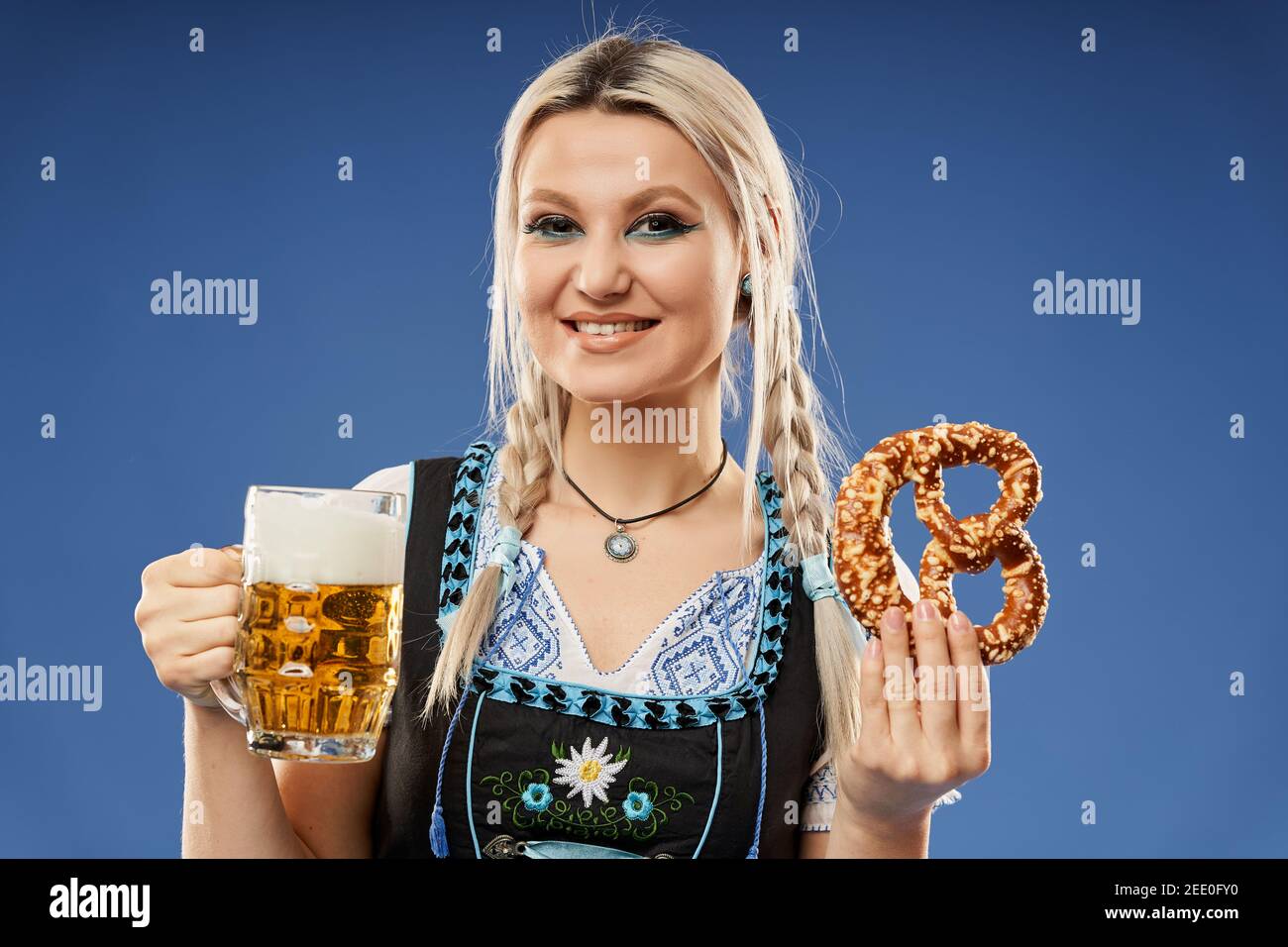 Blonde German young woman in traditional costume with a pint of beer ...
