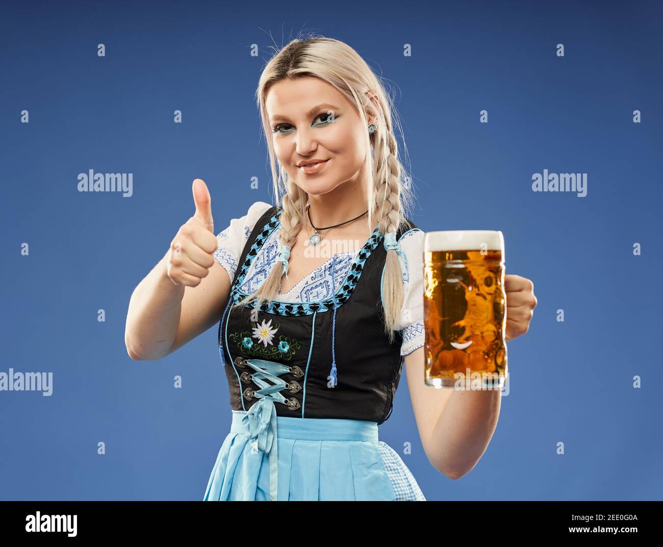 Blonde German young woman in traditional costume with a pint of beer ...