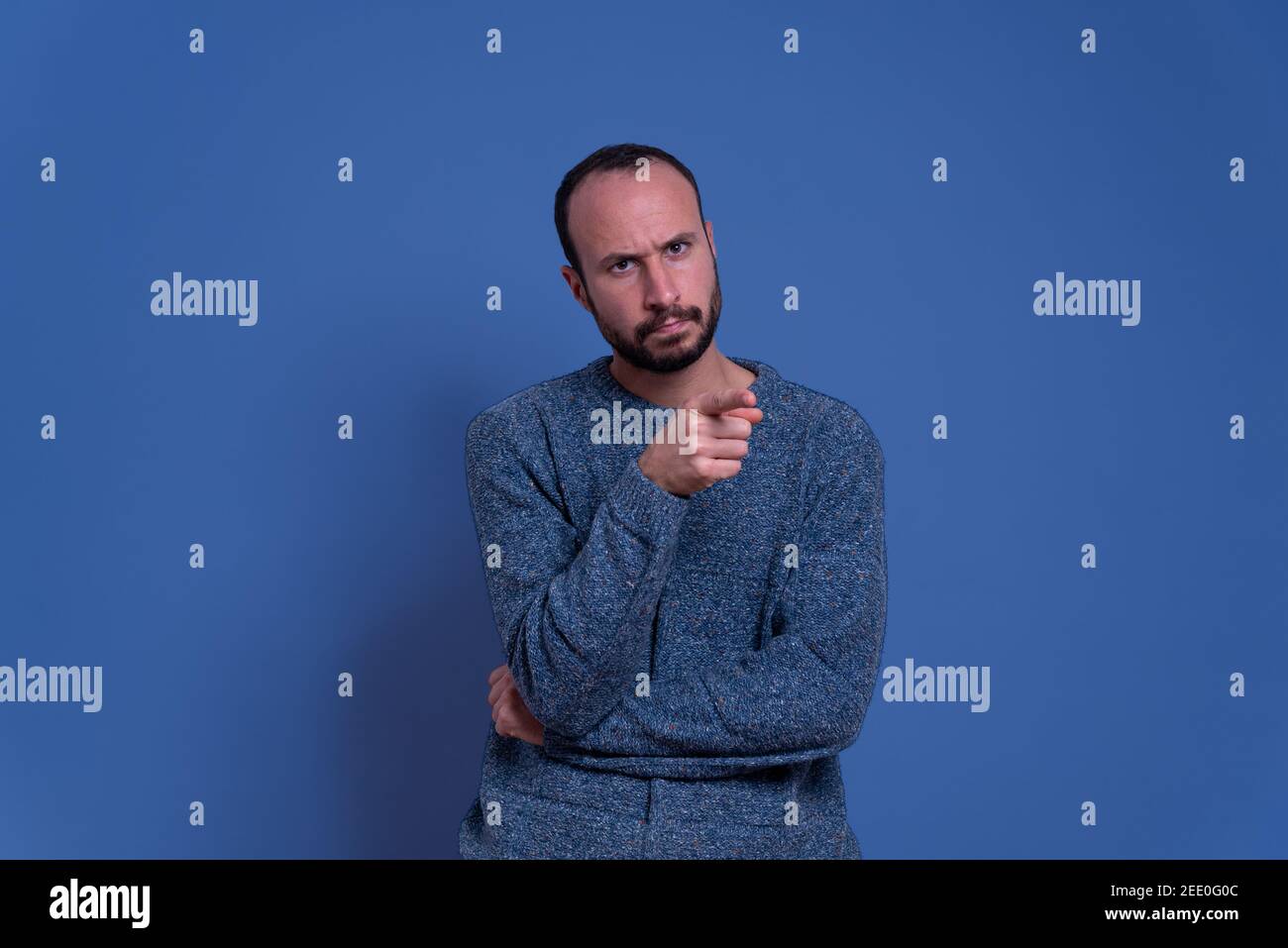 young man with severe and angry expression pointing finger in sign of ...