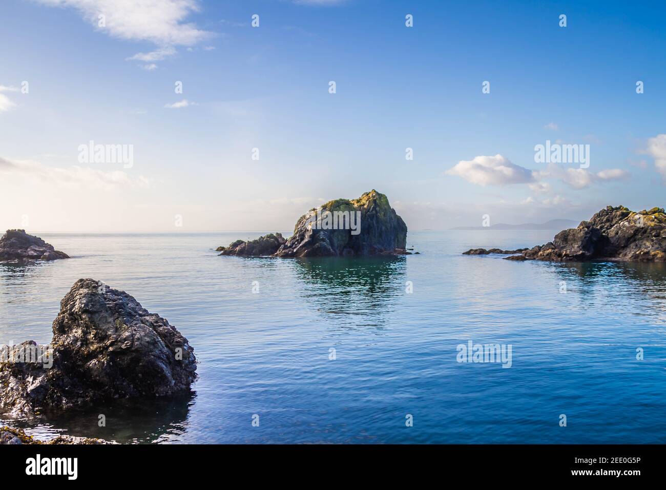 Rocks protruding from the surrounding blue ocean waters Stock Photo - Alamy