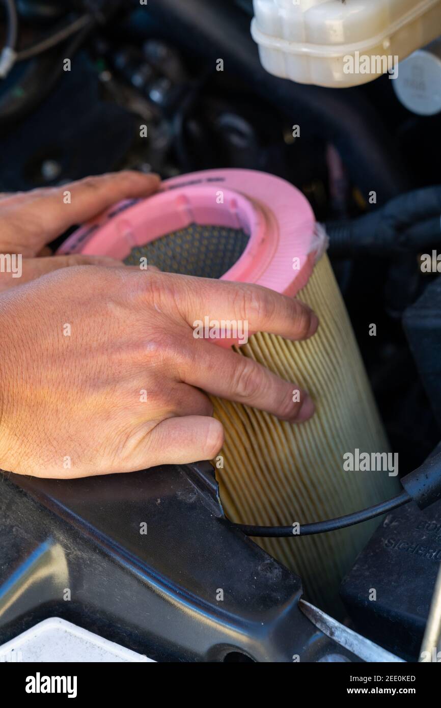 A close up of hands of a caucasian male car mechanic changing the air ...