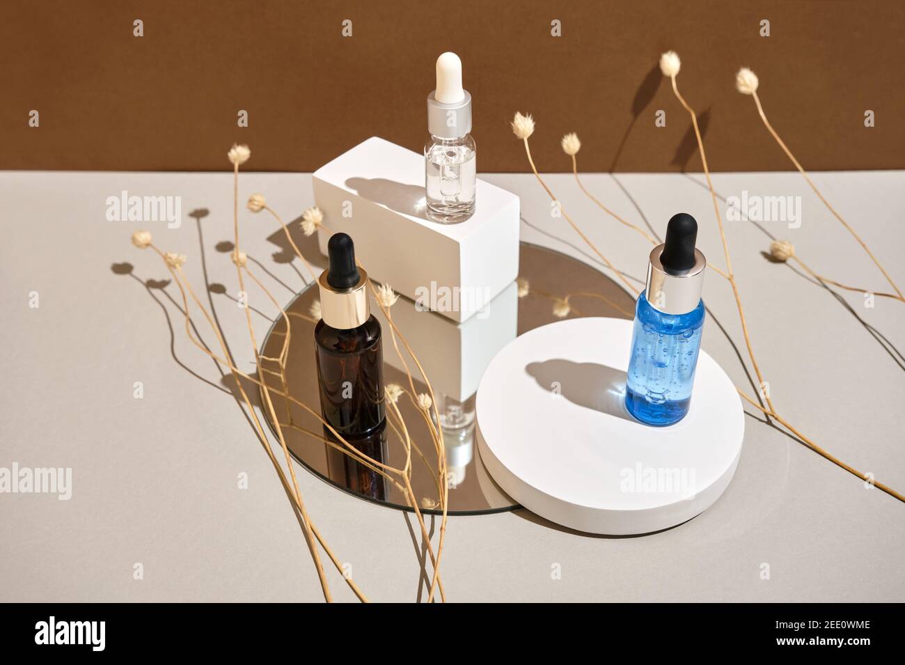 Bottle of serum stands on white round and rectangular podium, mirror ...