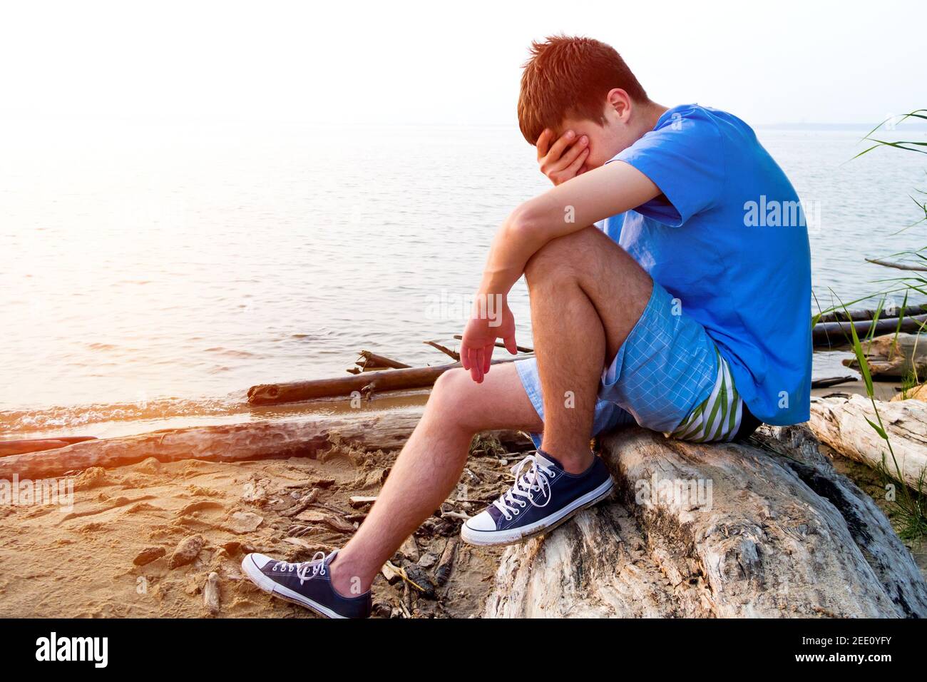 Sad Young Man sit on the Log at the Seaside Stock Photo - Alamy