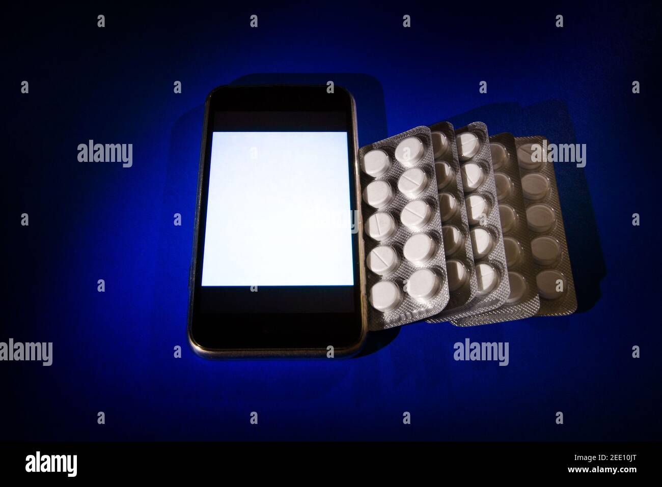 Mobile Phone with a Pills on the Blue Paper Background in the Dark ...