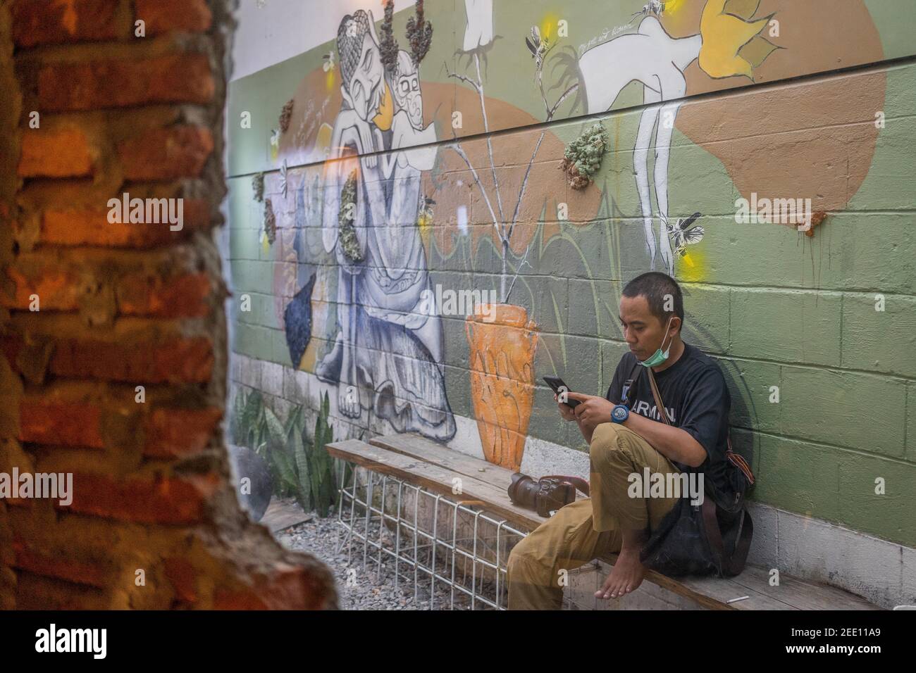 A visitor sits relaxed on his mobile phone on a background of one of ...