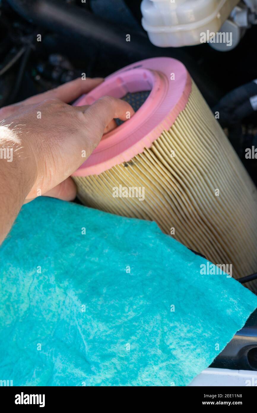 A close up of hands of a caucasian male car mechanic changing the air ...