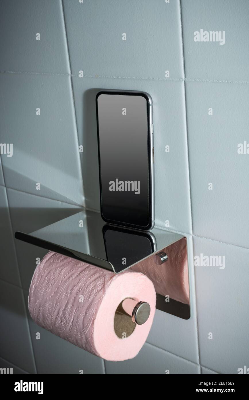 Mobile phone in toilet with pink toilet paper against white tile ...