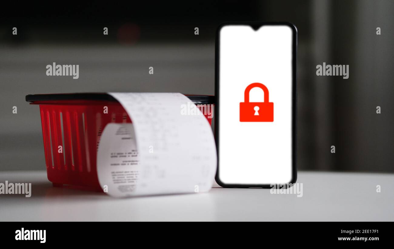 Padlock icon on smartphone screen next to red shopping basket and ...