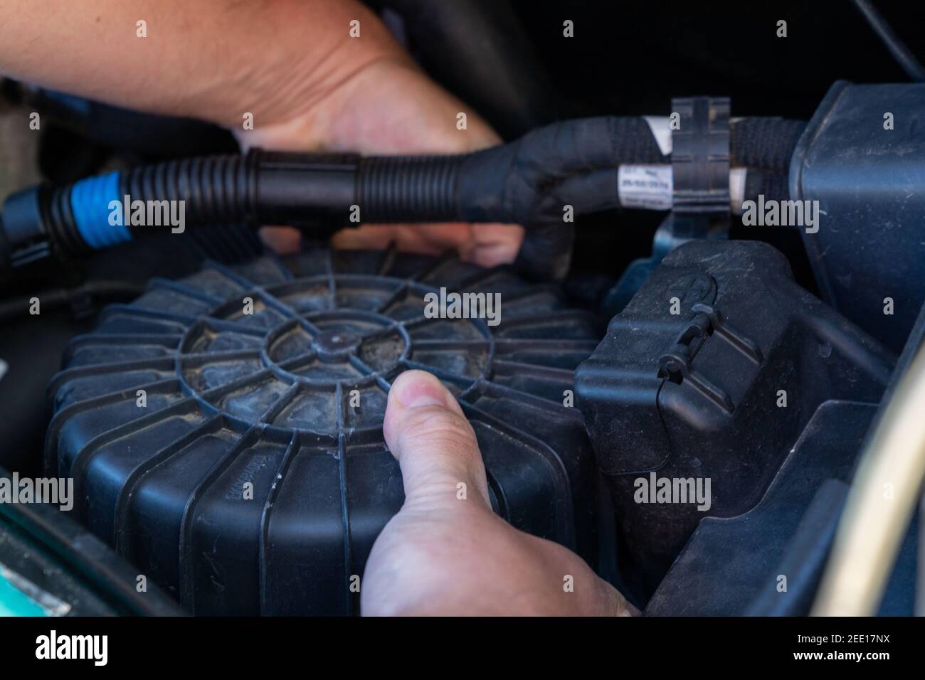 A close up of hands of a caucasian male removing the air filter cover ...