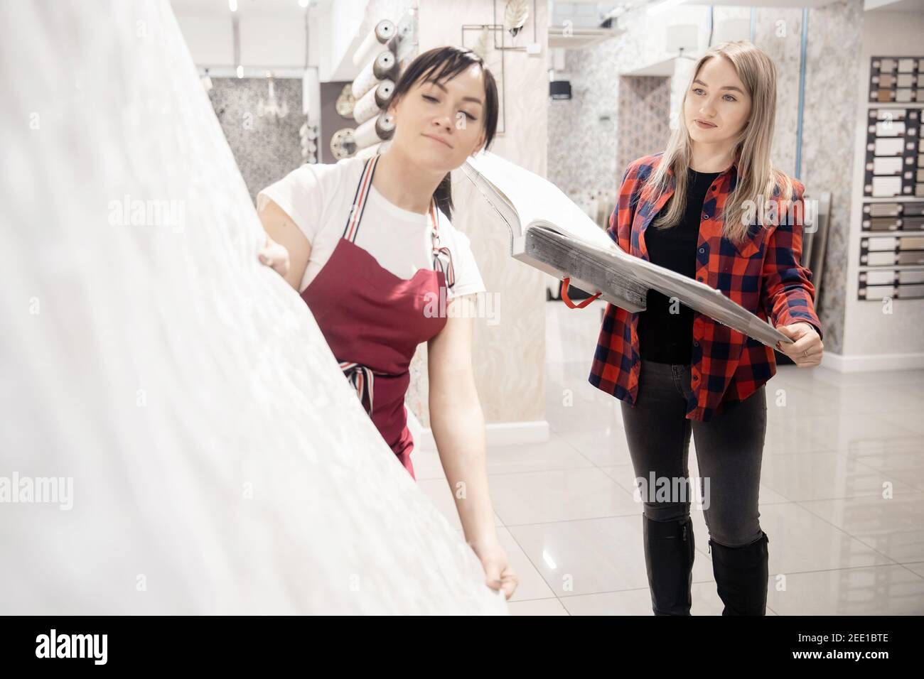 Renovation store, sales assistant shows rolls of wallpaper for home ...
