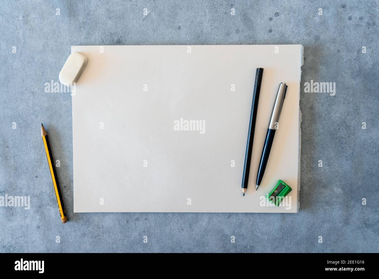 Top view of blank drawing sheet with pencils, pen, sharpener and eraser ...