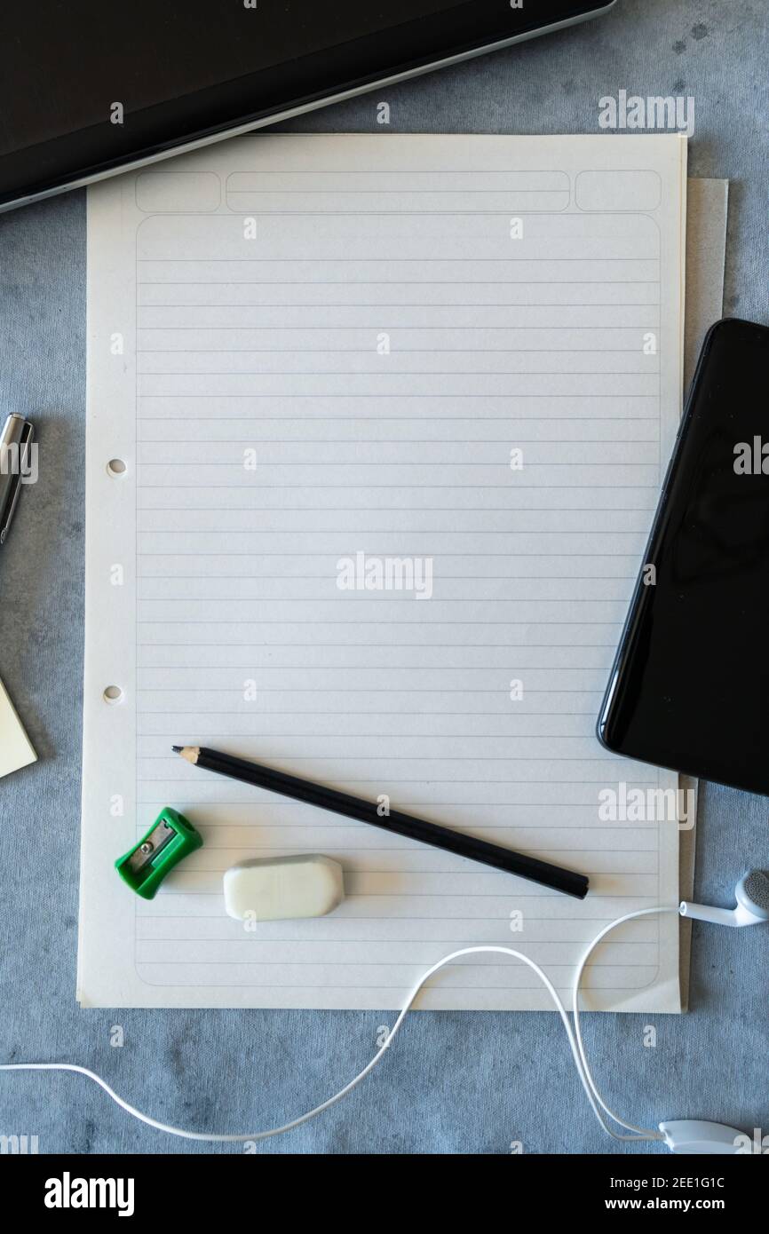 Top view of a blank sheet with smartphone, earphones, pencil, eraser ...