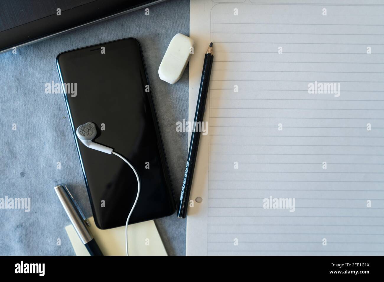 Top view of a blank sheet with smartphone, earphones, pen, pencil and ...