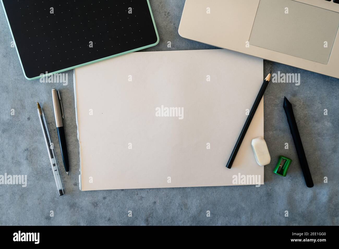 Top view of blank drawing sheet with pencils, pens and graphic tablet ...