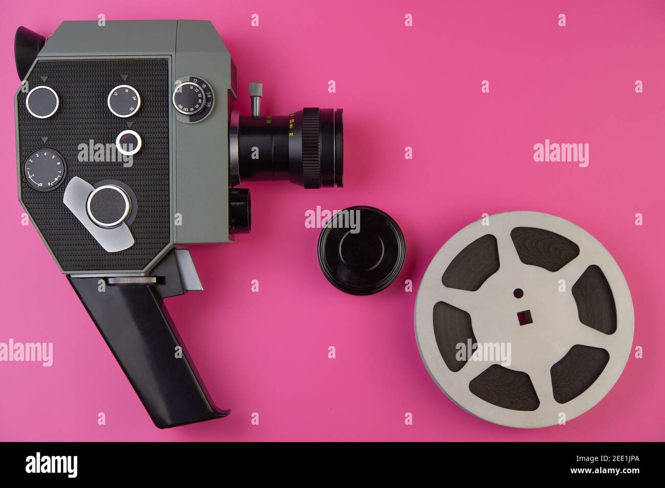 vintage movie camera lies on a pink background and a reel of film ...