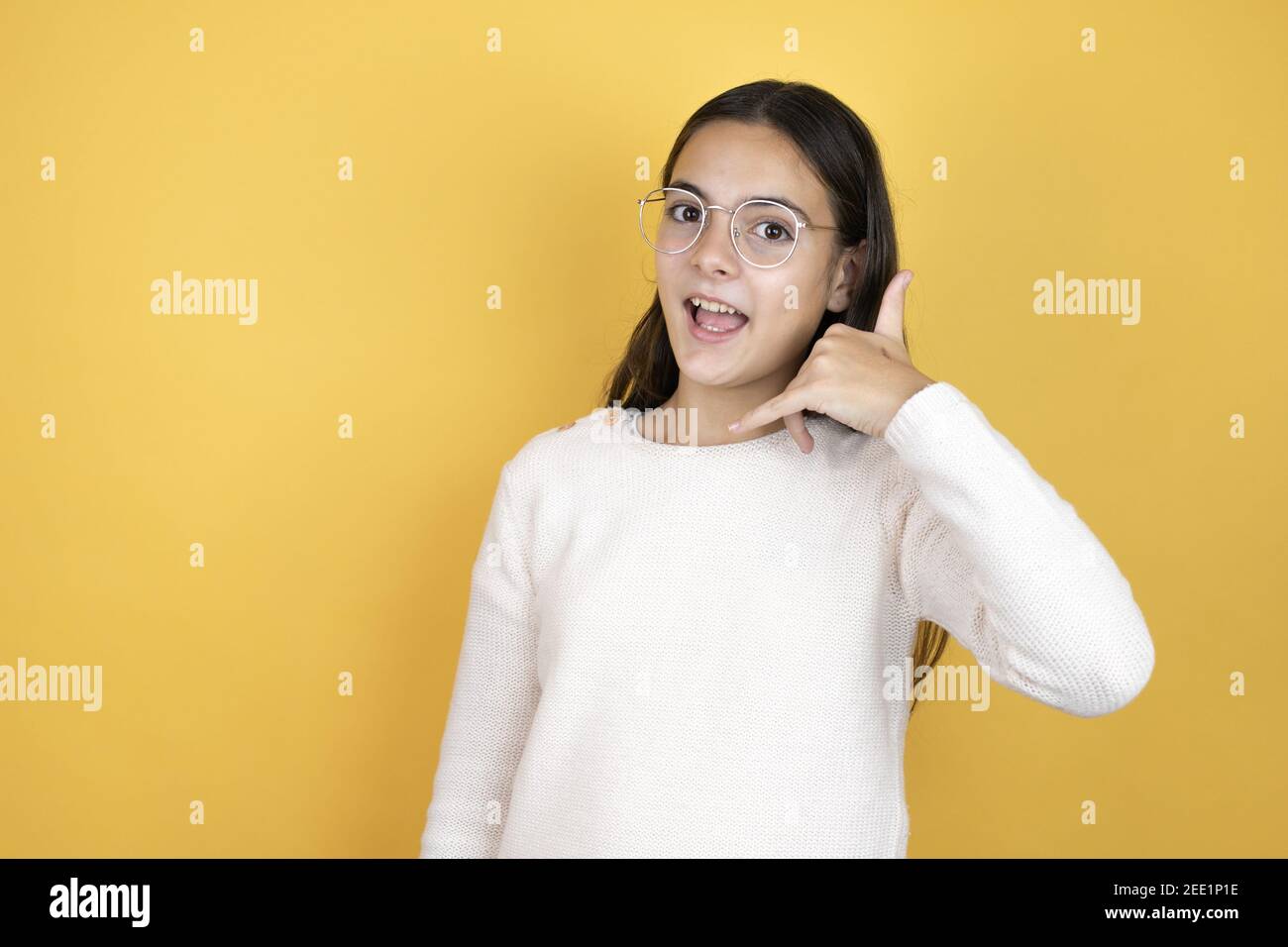 Beautiful child girl wearing casual clothes smiling doing phone gesture ...