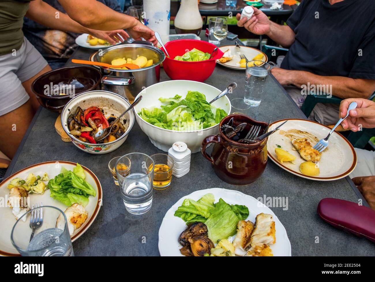 People at table full of food. Barbecue, lunch or dinner. (Fried fish ...