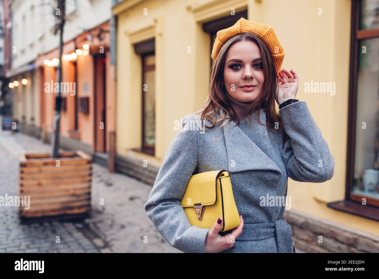 Portrait of stylish young woman wearing yellow knitted beret, grey coat ...
