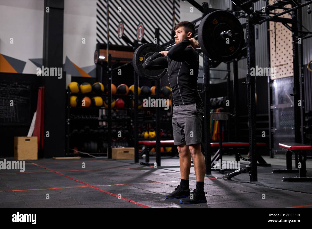 young man with big muscles holding heavy weight for cross fit swing ...